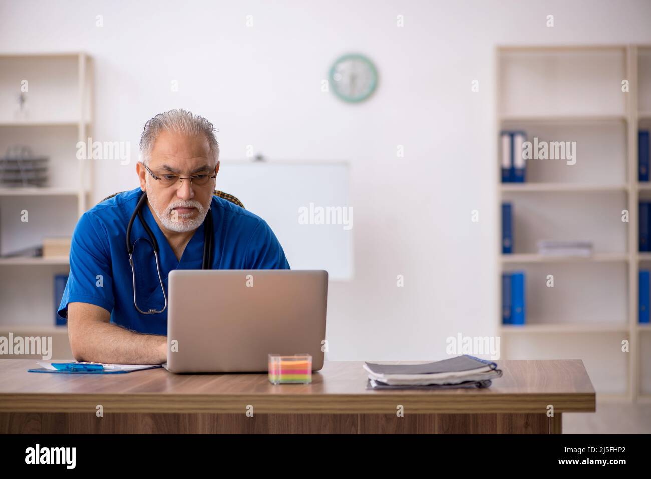 Old male doctor working at the hospital Stock Photo - Alamy