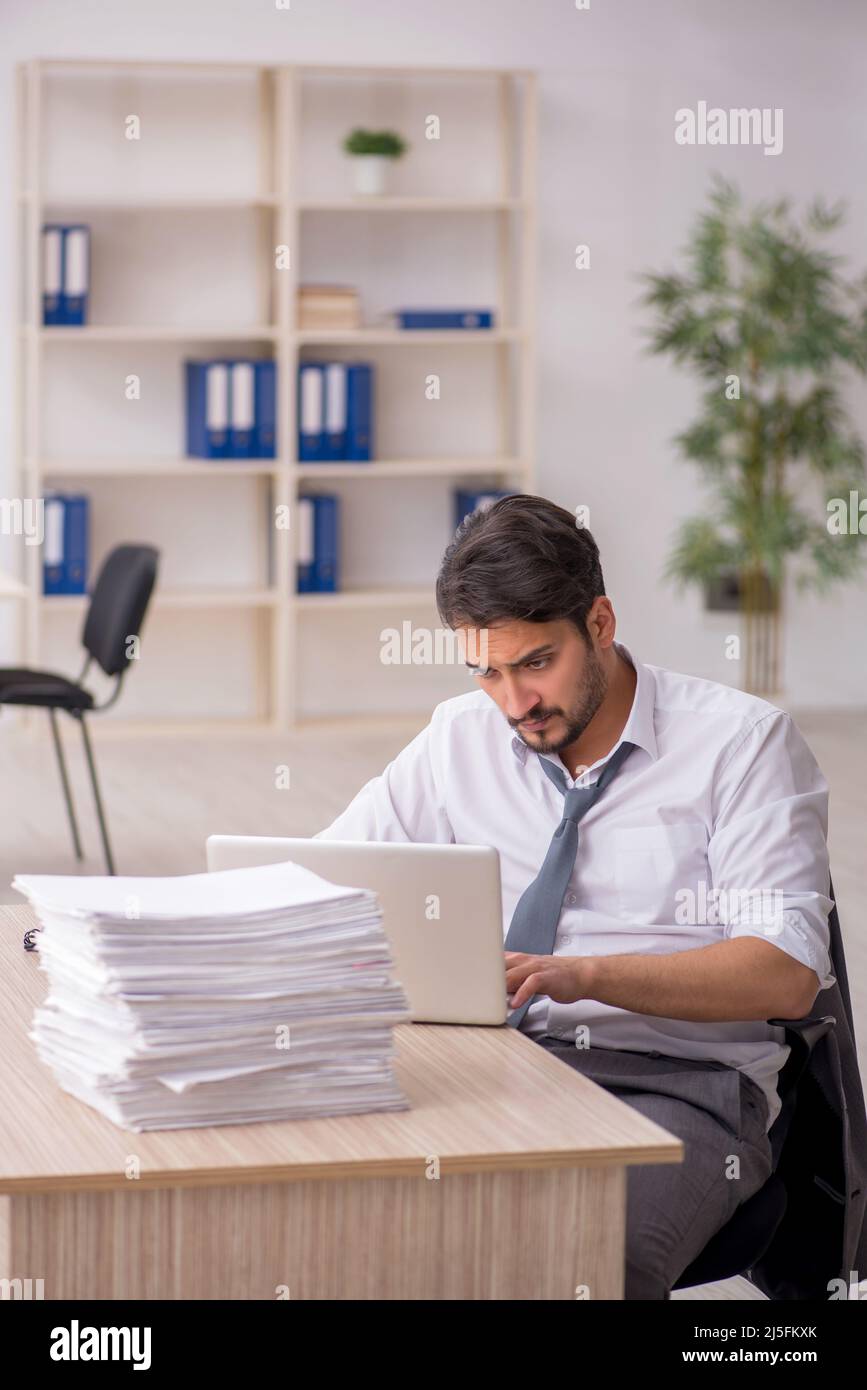 Young male employee and too much work at workplace Stock Photo - Alamy