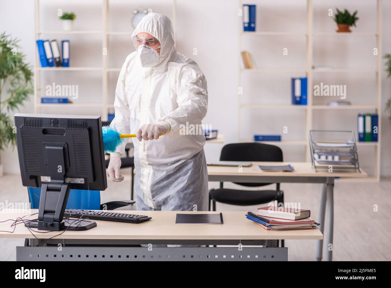 Old contractor cleaning the office holding feather Stock Photo - Alamy