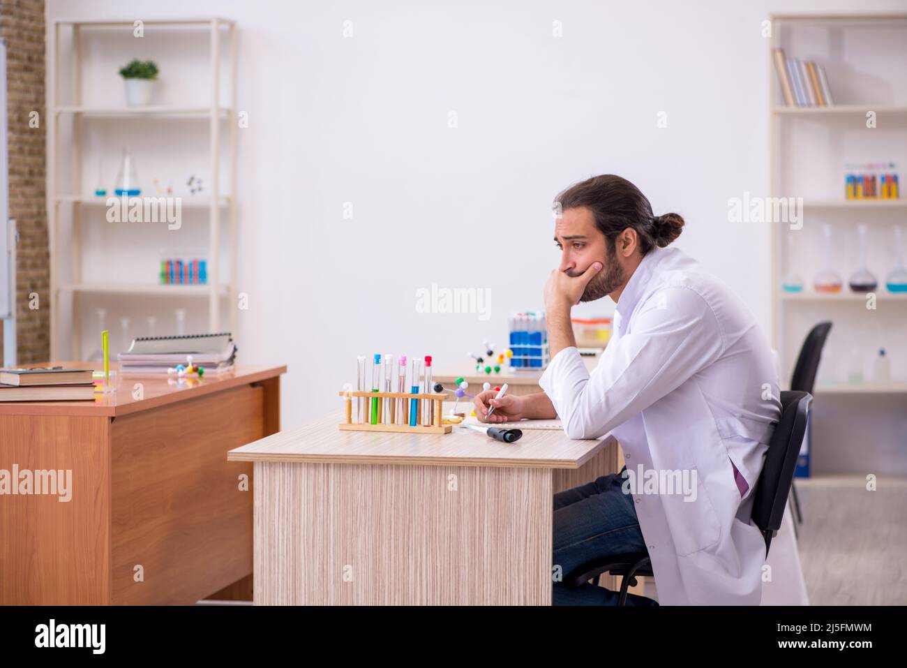 Young chemist sitting at the desk in the classroom Stock Photo - Alamy