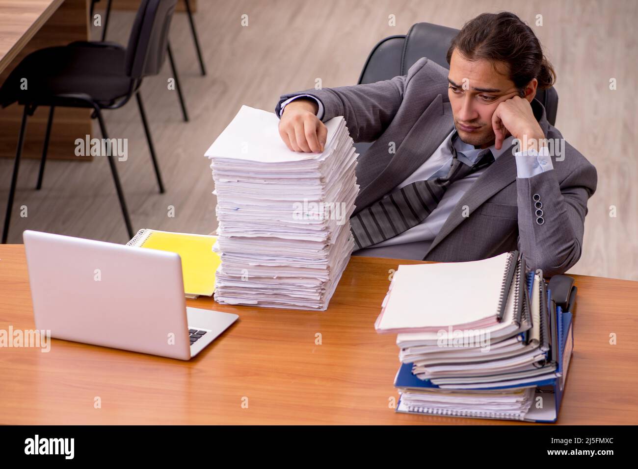 Young employee and too much work in the office Stock Photo - Alamy