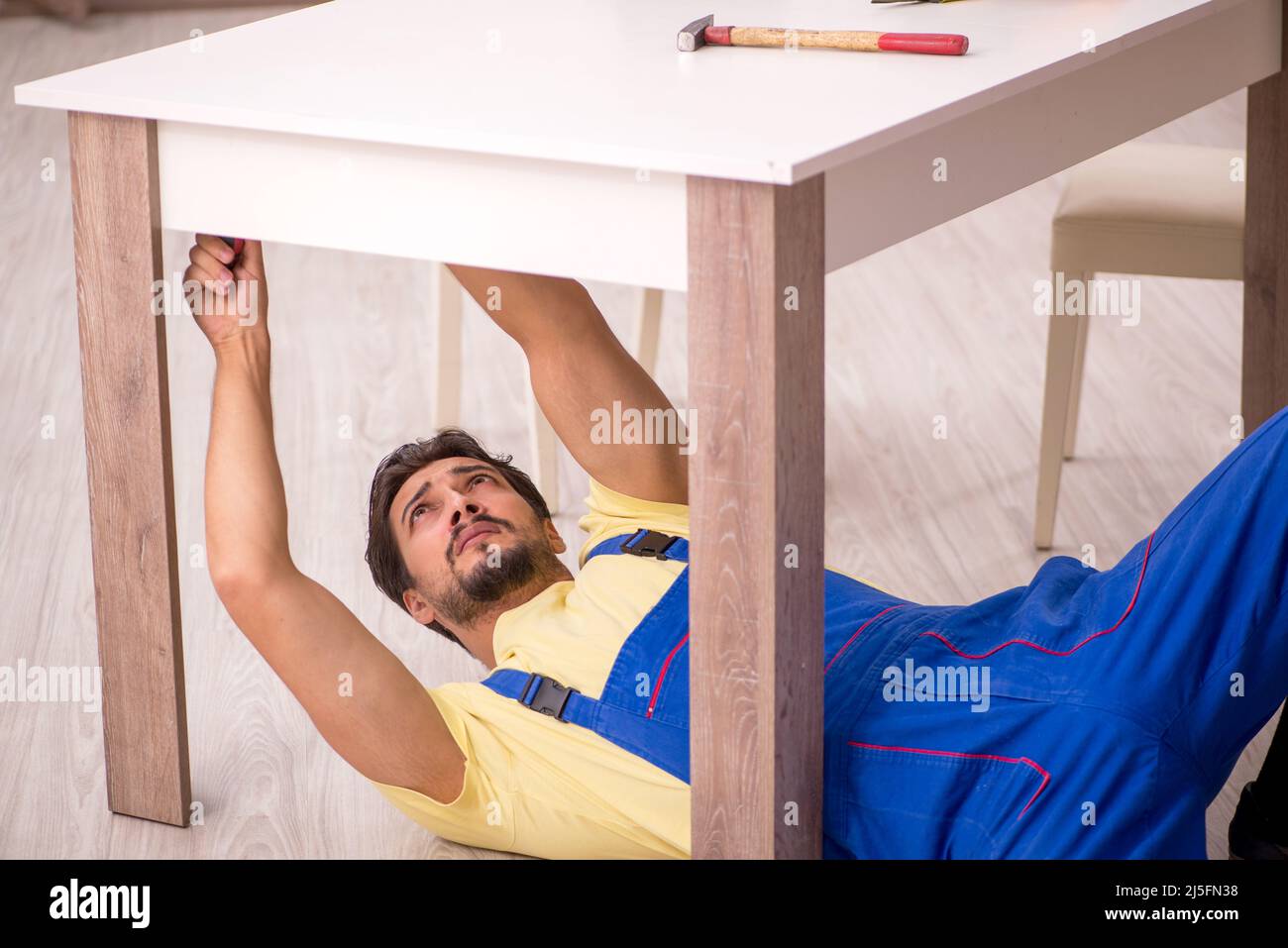 Young carpenter repairing table at home Stock Photo - Alamy
