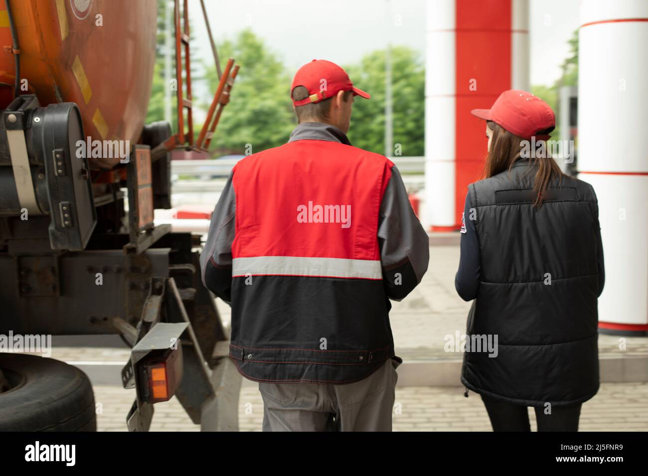 Refueling at a gas station. Employees of the fuel company stand near ...