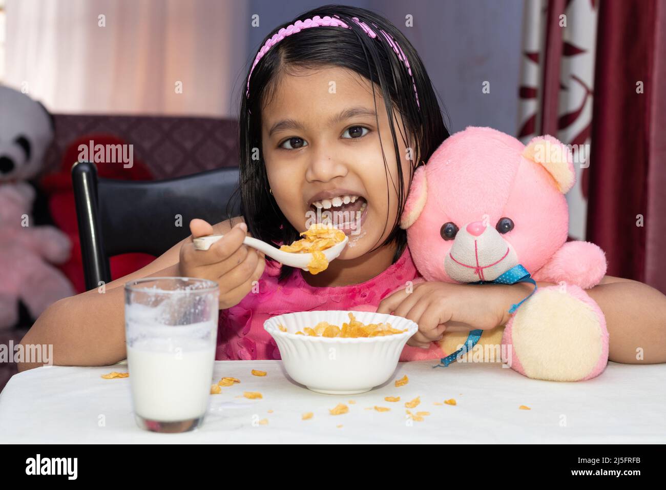 An Indian girl child eating cereal with milk with smiling face and ...