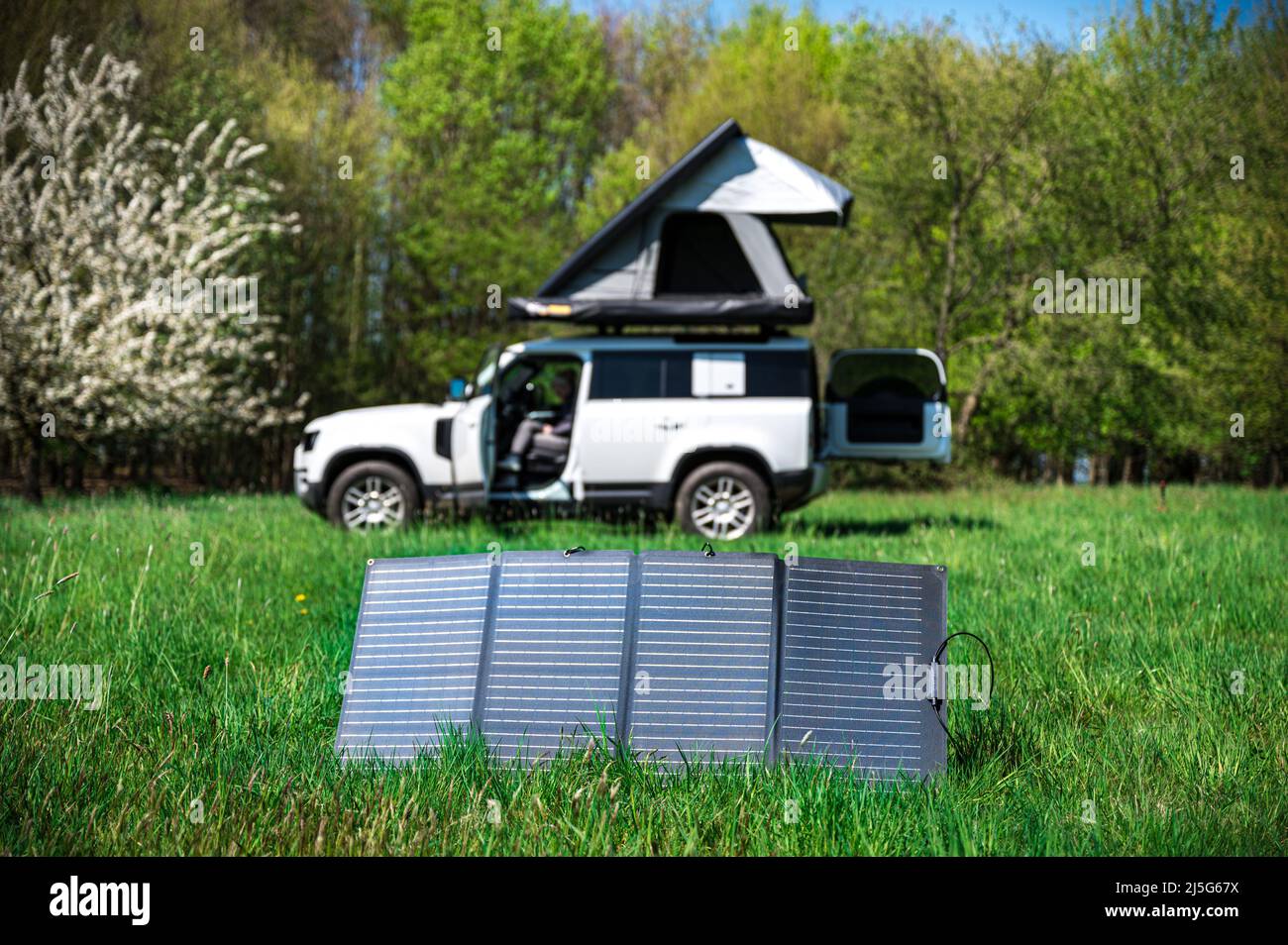 4x4 Offroad vehicle camping with roof tent in a meadwow with solar ...