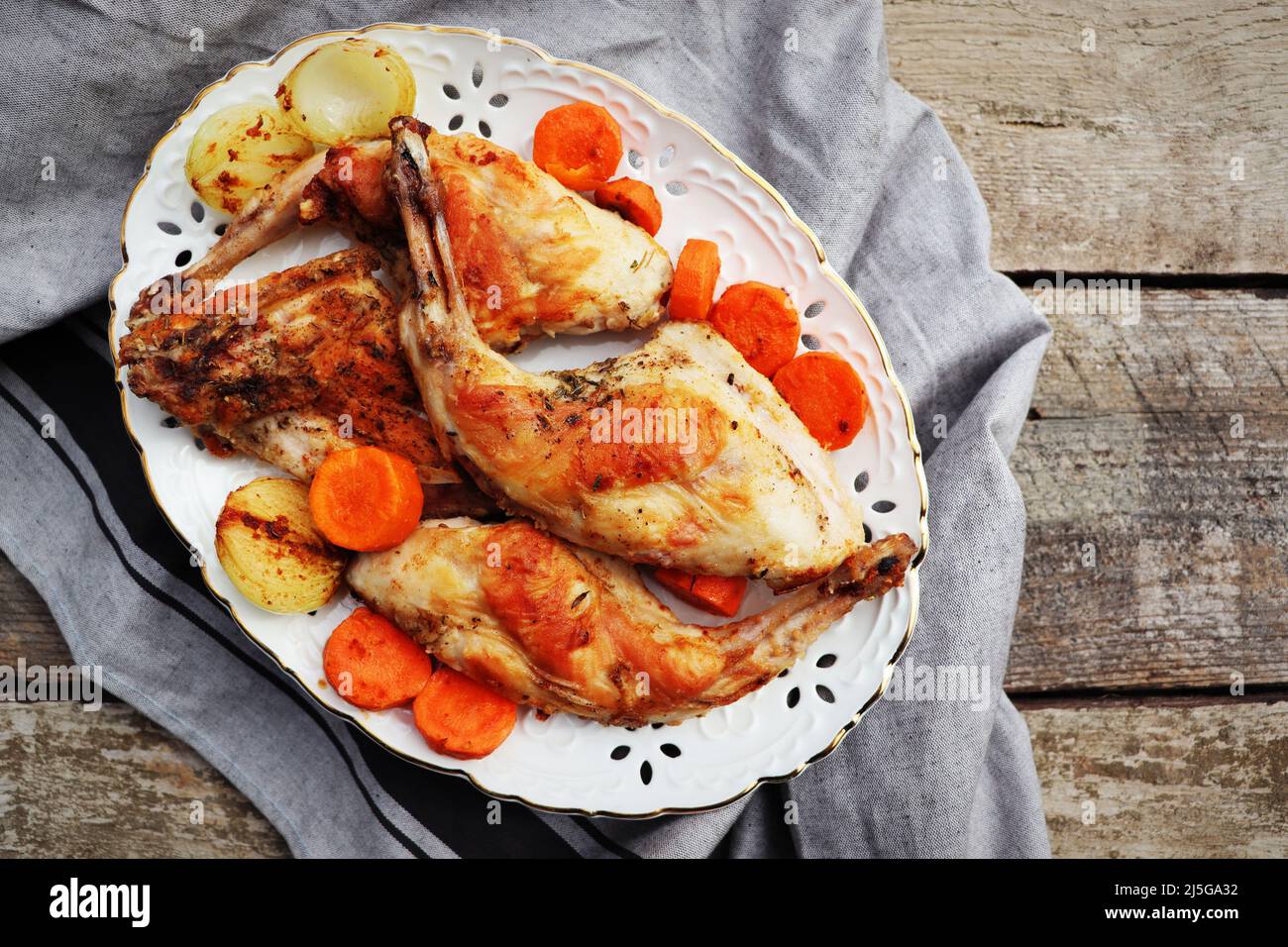Roasted Rabbit Haunches on white plate with Stewed Vegetables on Rustic ...