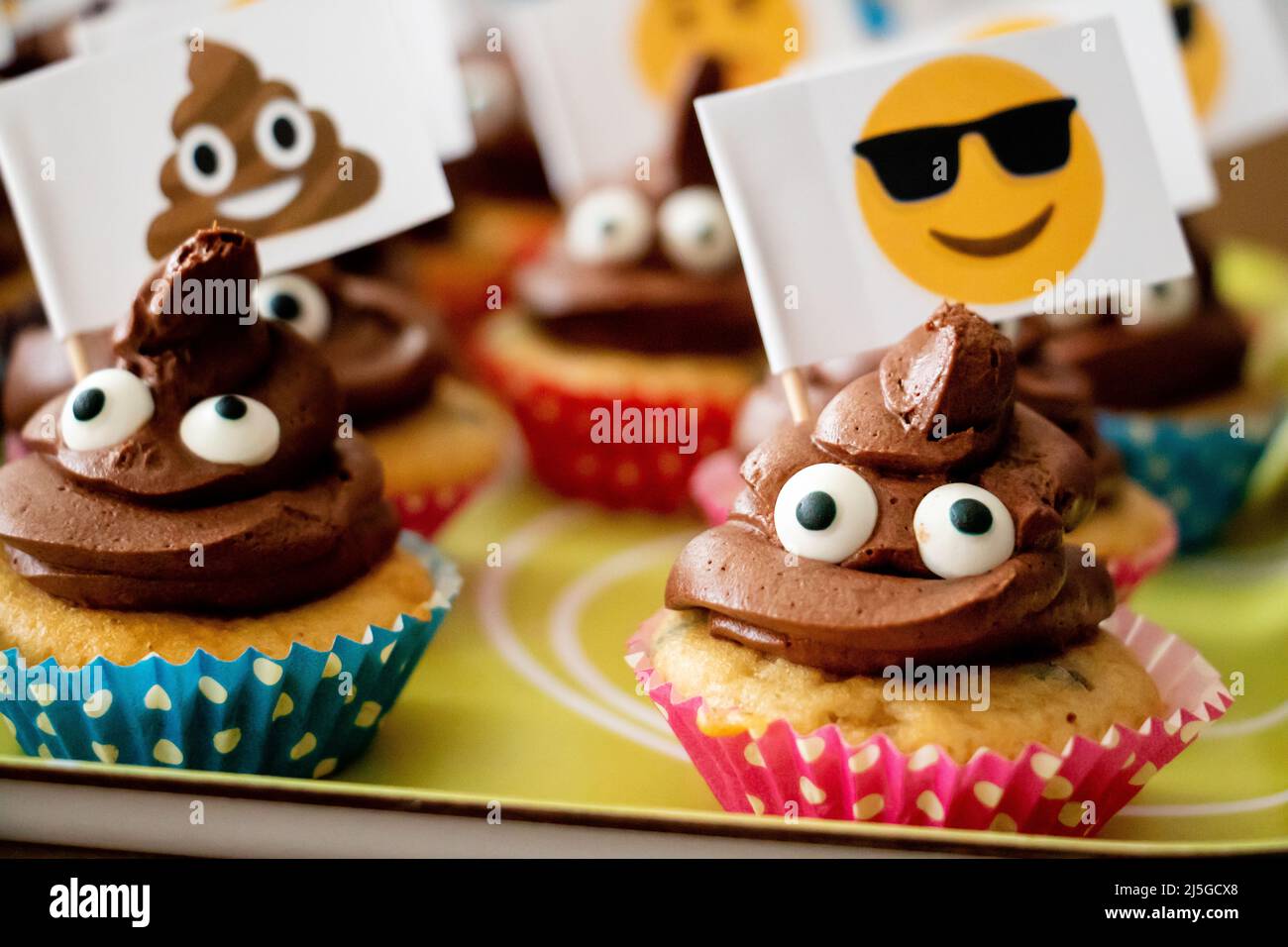 "Pile of poo" emoji cupcakes. Each with a flag of another emoji Stock ...