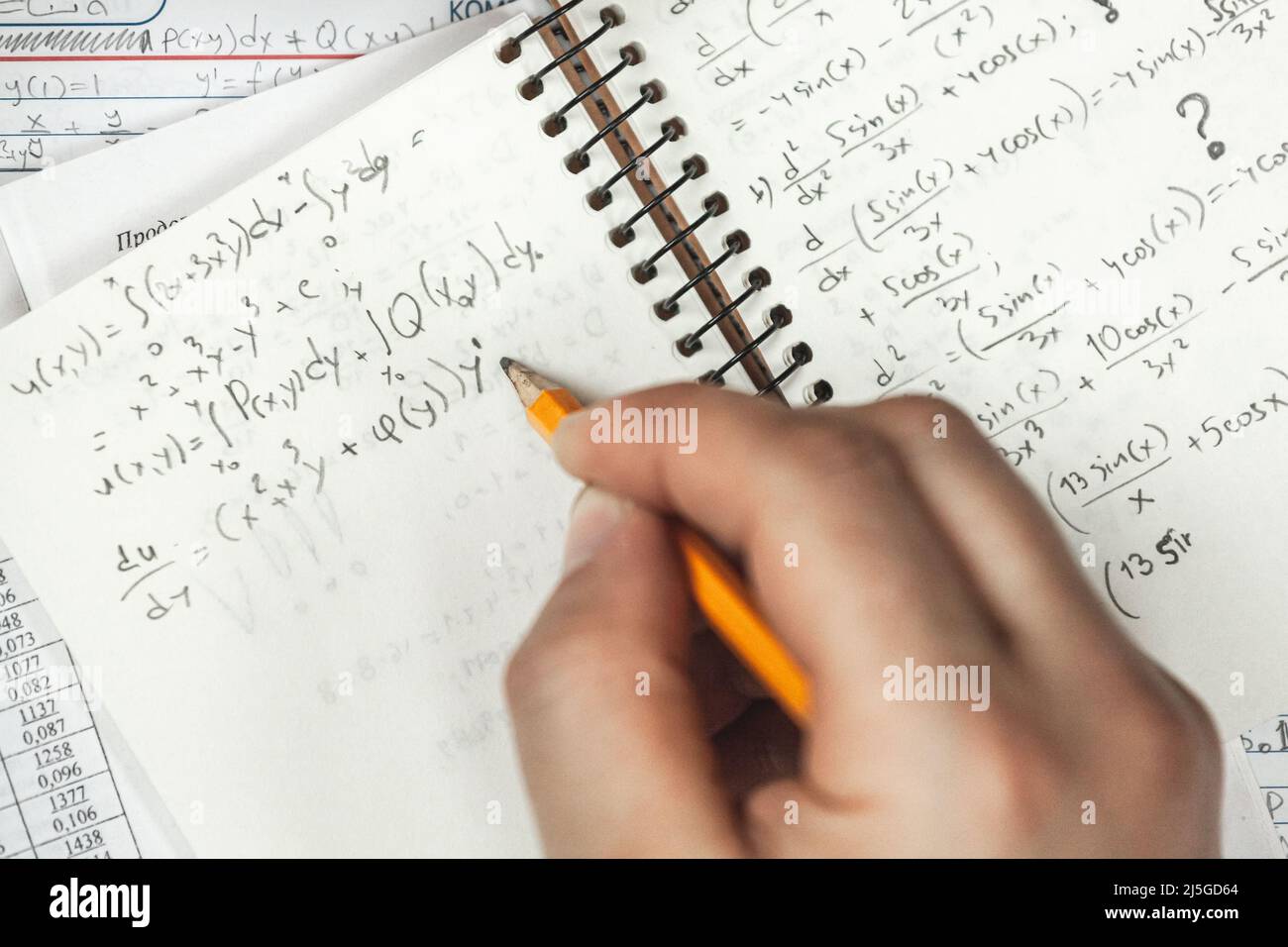 Math formulas are written in pencil in a notebook holding man in Stock ...