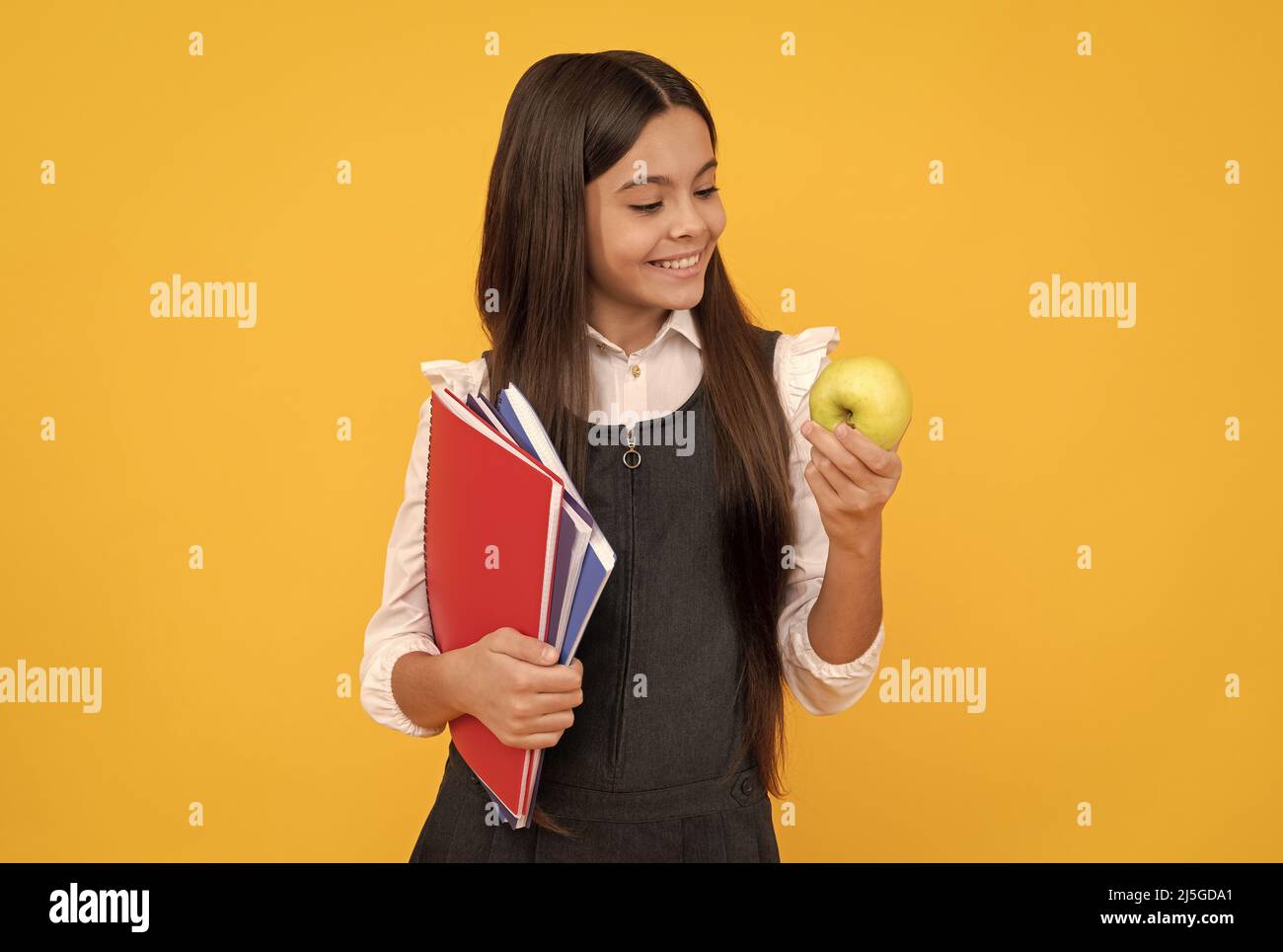 Snack time. Happy girl look at apple holding schoolbooks. School snack ...