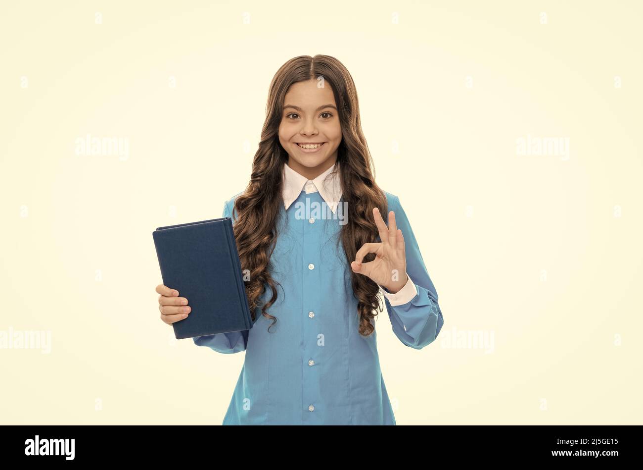 Happy primary school pupil hold library book showing OK sign isolated ...