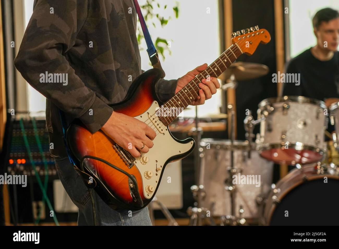 The guy plays the electric guitar to record the sound. He holds a ...