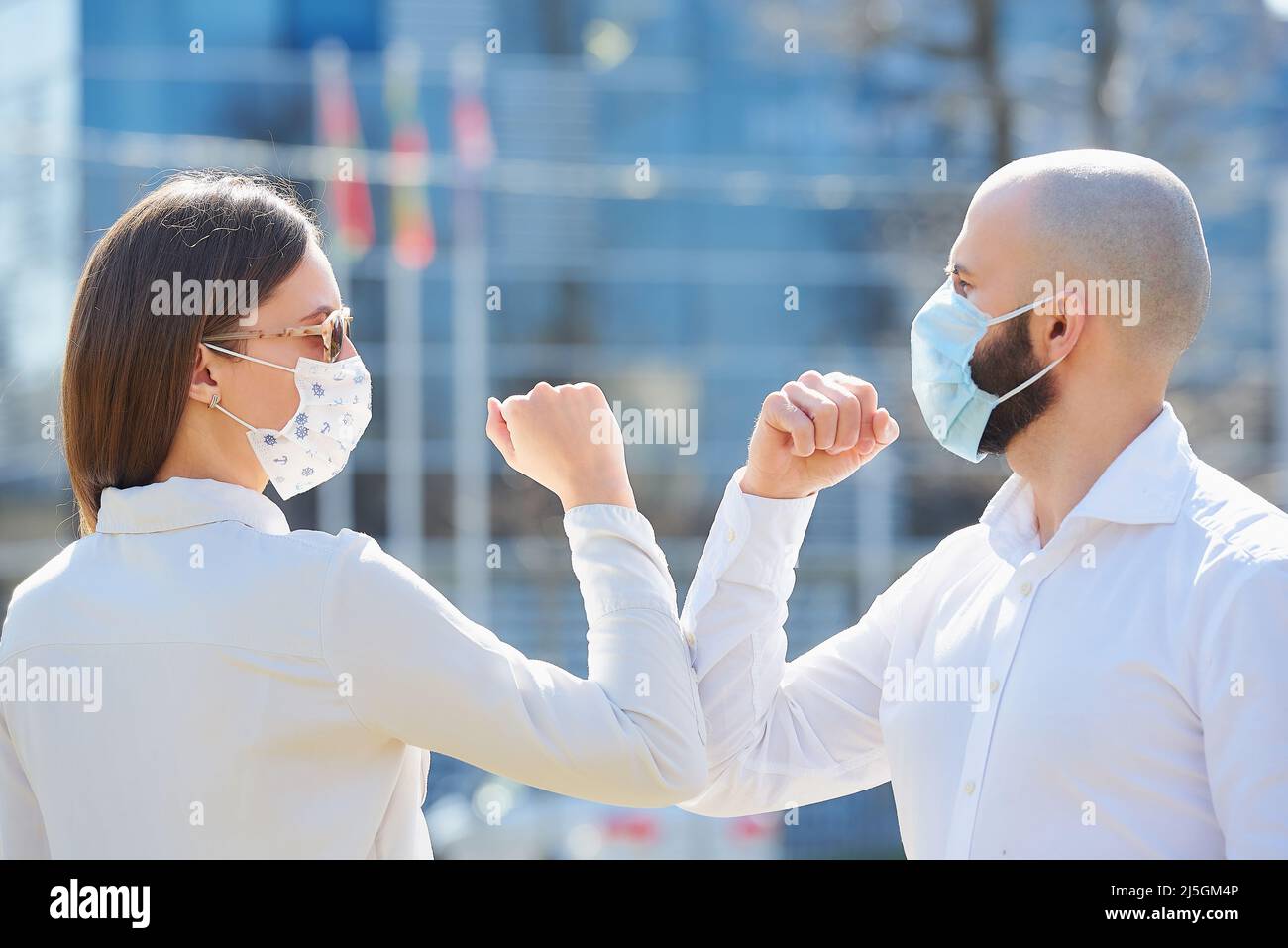 Instead of greeting with hug or handshake man and woman bump elbows on ...