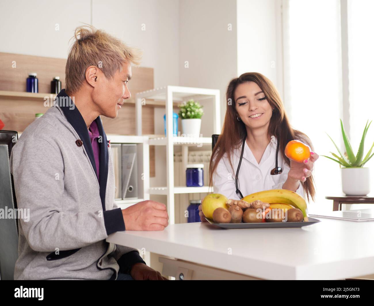 young female nutritionist in office suggests eating fruits to her ...