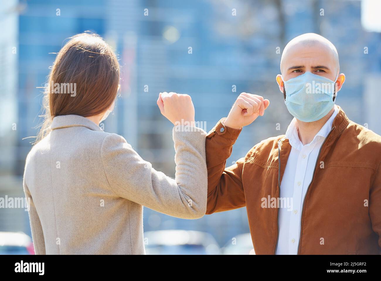 Instead of greeting with hug or handshake man and woman bump elbows on ...