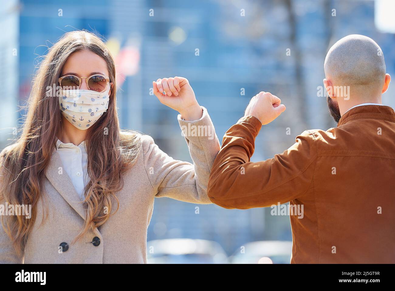 Instead of greeting with hug or handshake man and woman bump elbows on ...