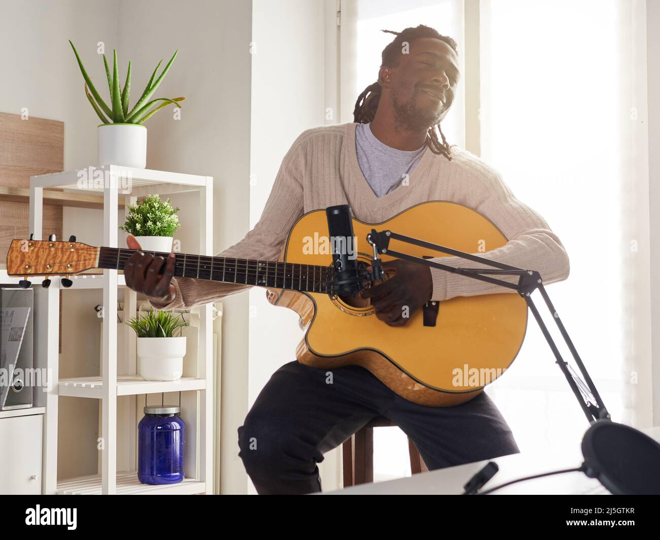 Young man is singing and playing guitar while making an audio recording ...
