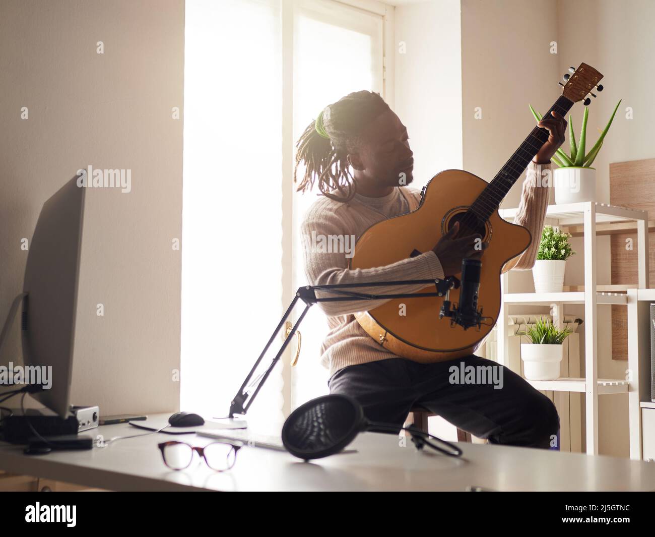 Young man is singing and playing guitar while making an audio recording ...