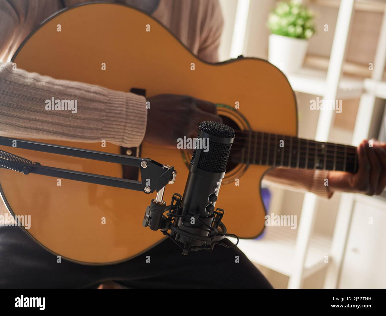Young man is singing and playing guitar while making an audio recording ...