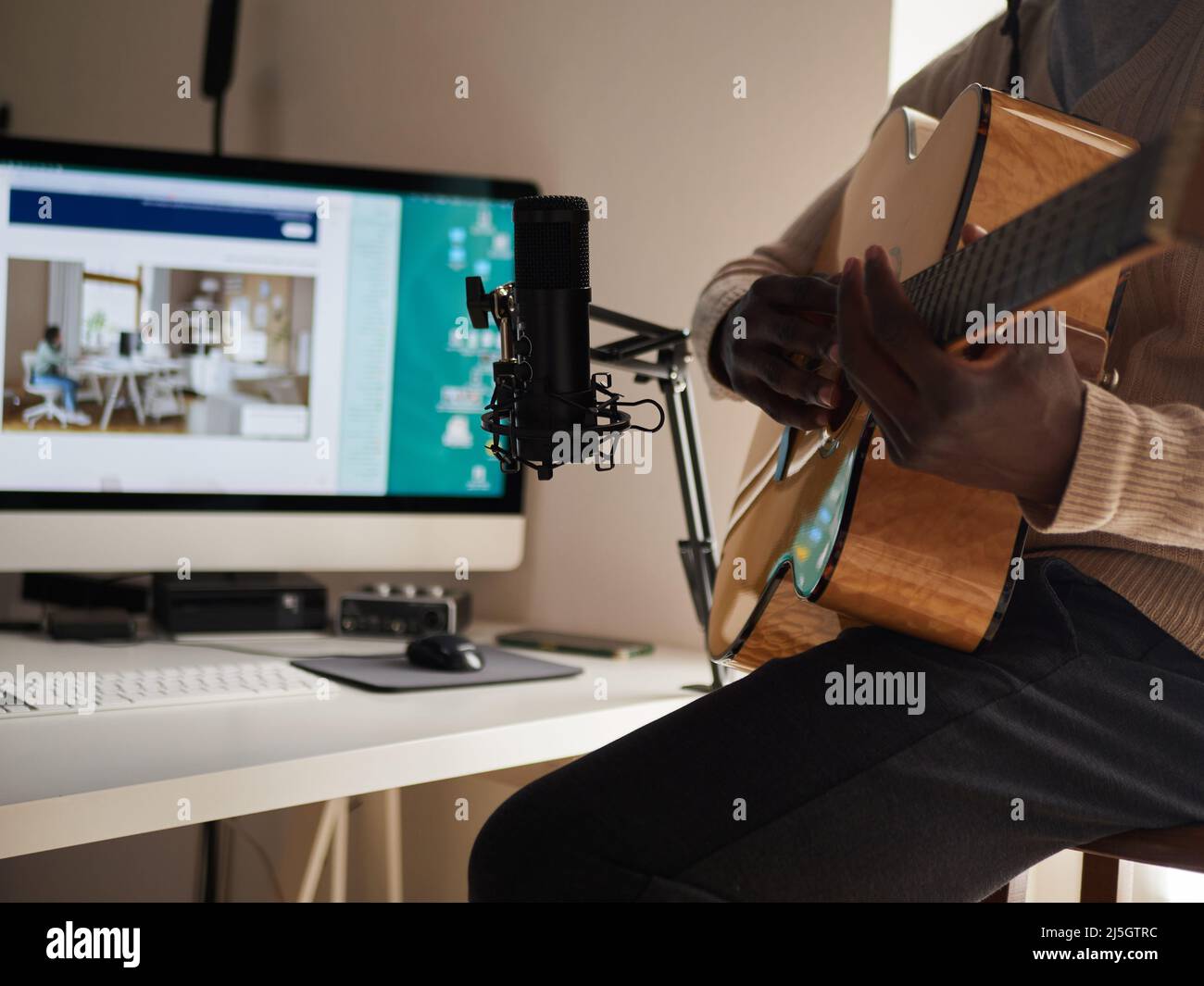 Young man is singing and playing guitar while making an audio recording ...