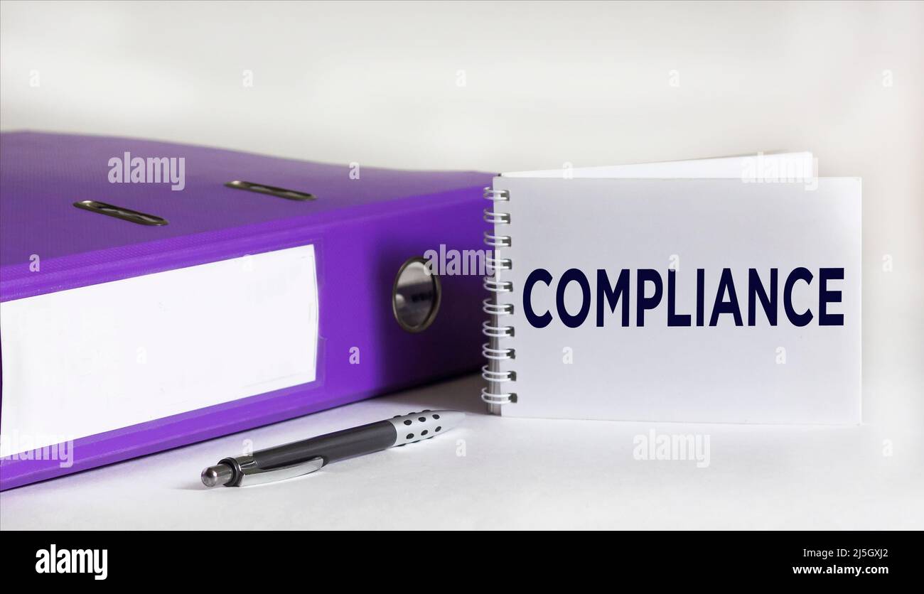 Notepad with Compliance text, on white background with folder and pen ...