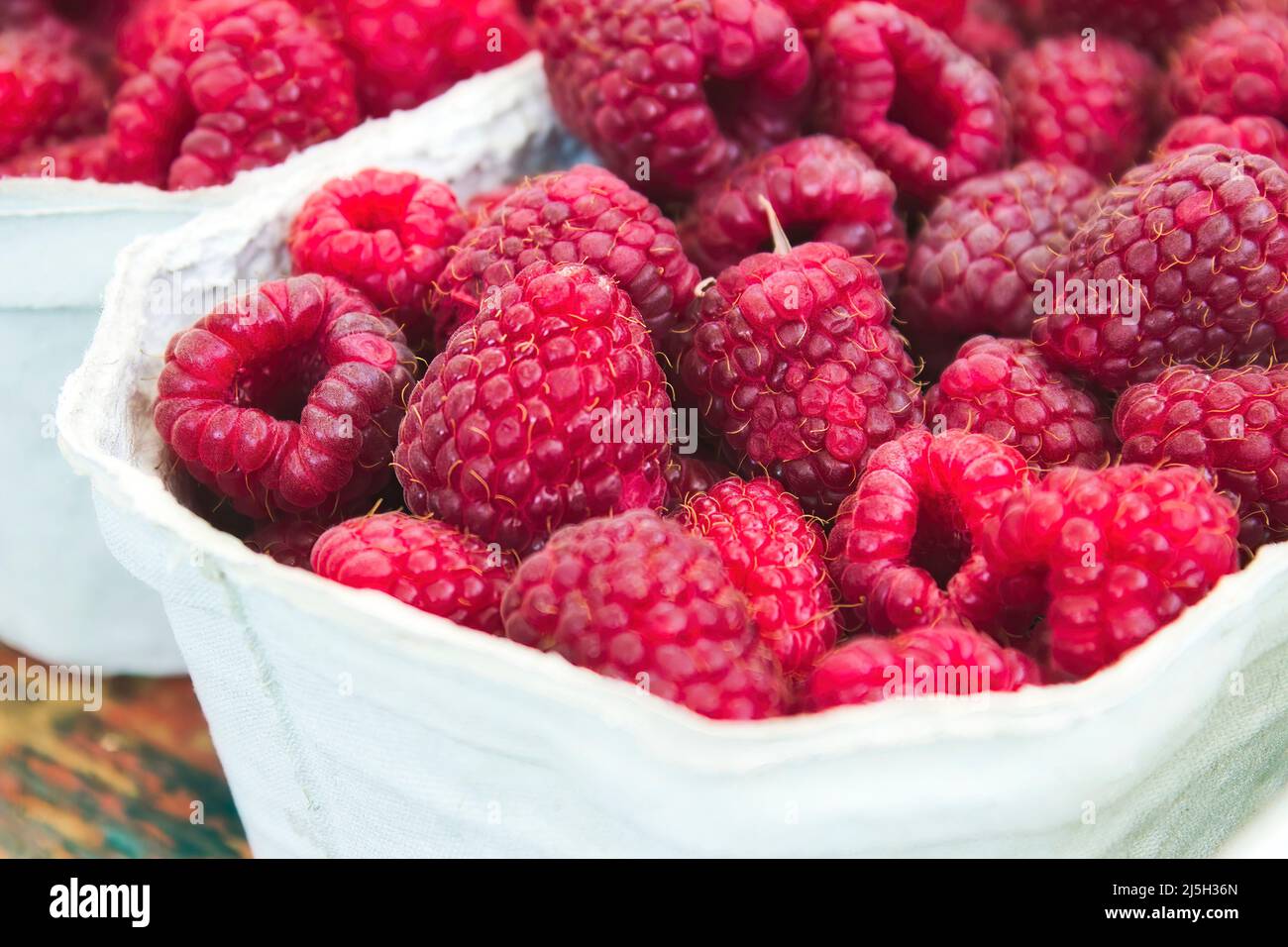 Close-up of a container of fresh, red, ripe raspberries at an open-air ...