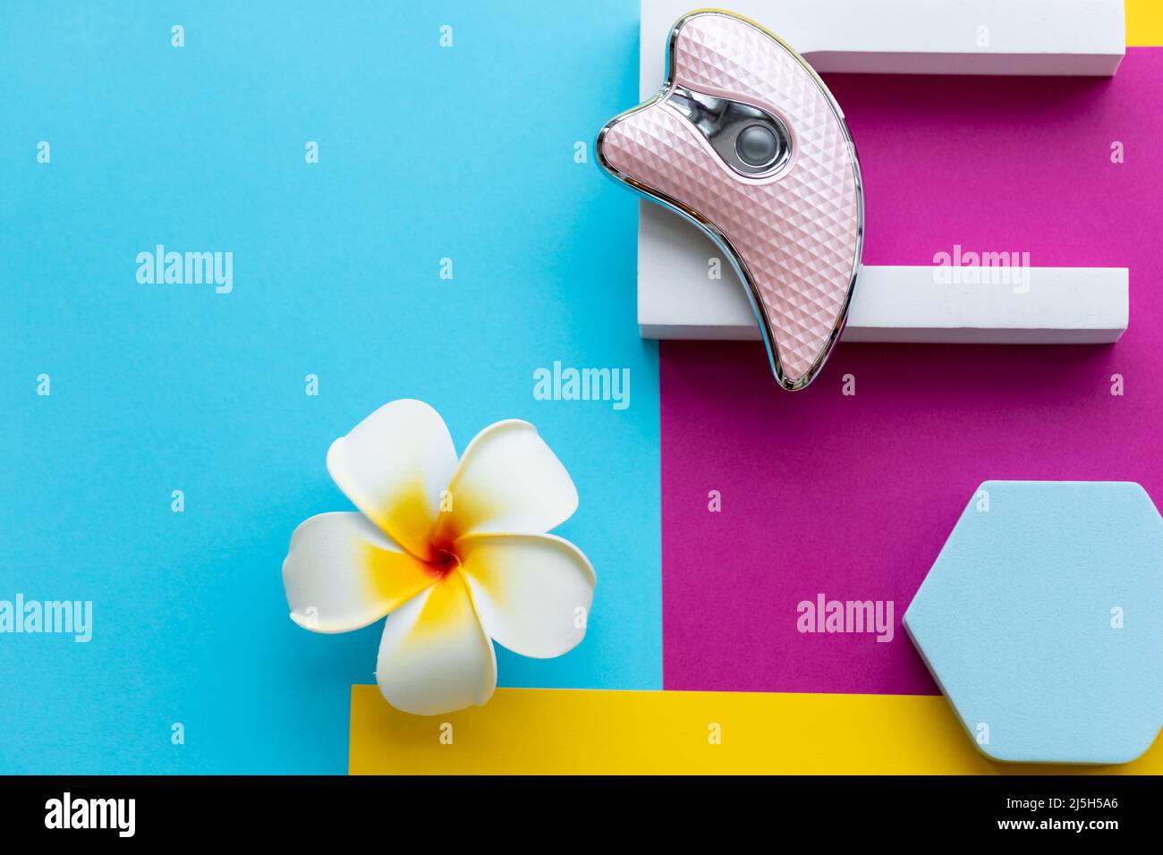 microcurrent facial toning device on pink background with green leaves ...