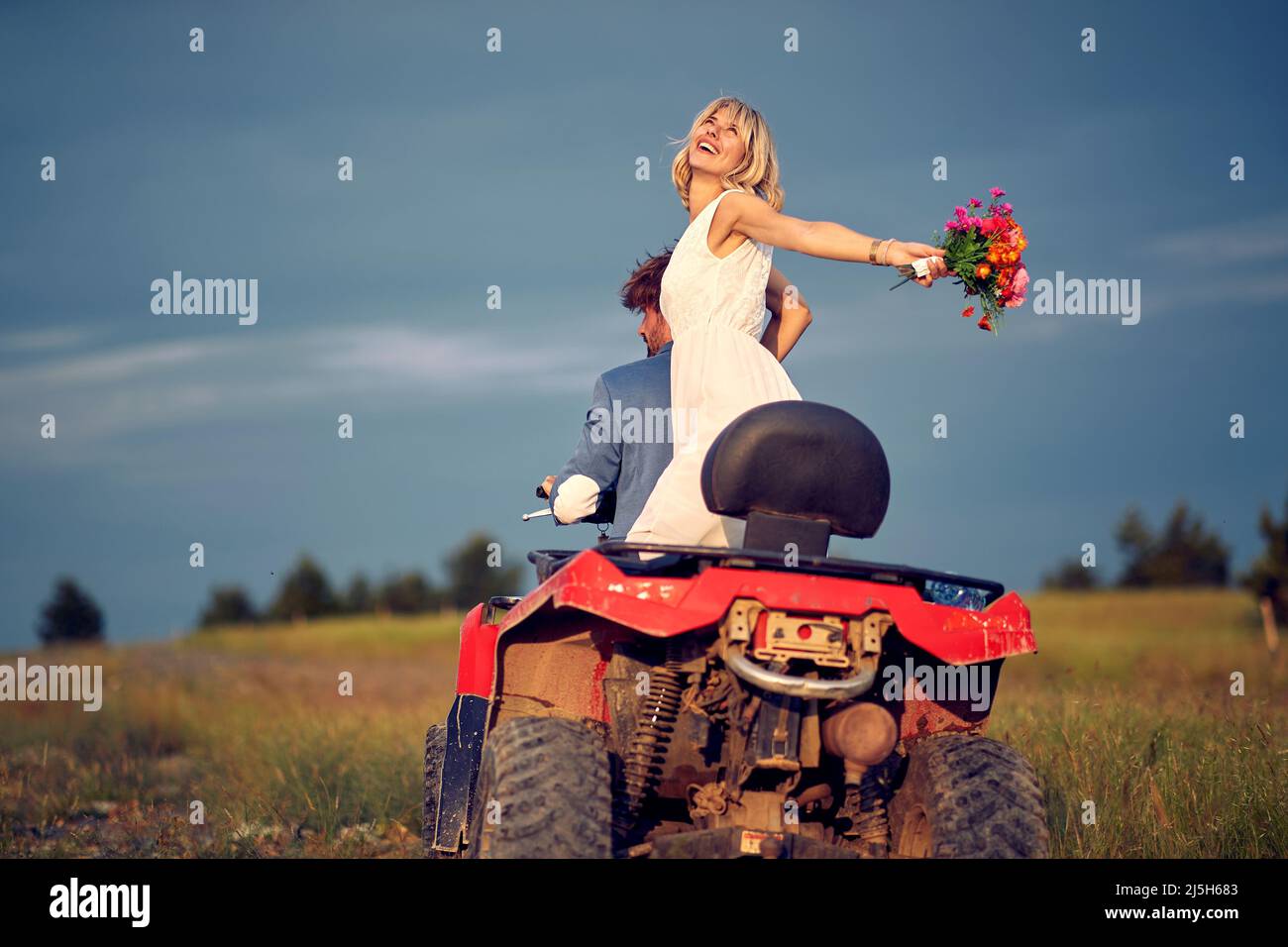 Adorable newlyweds driving quad together in the nature; Rural wedding ...