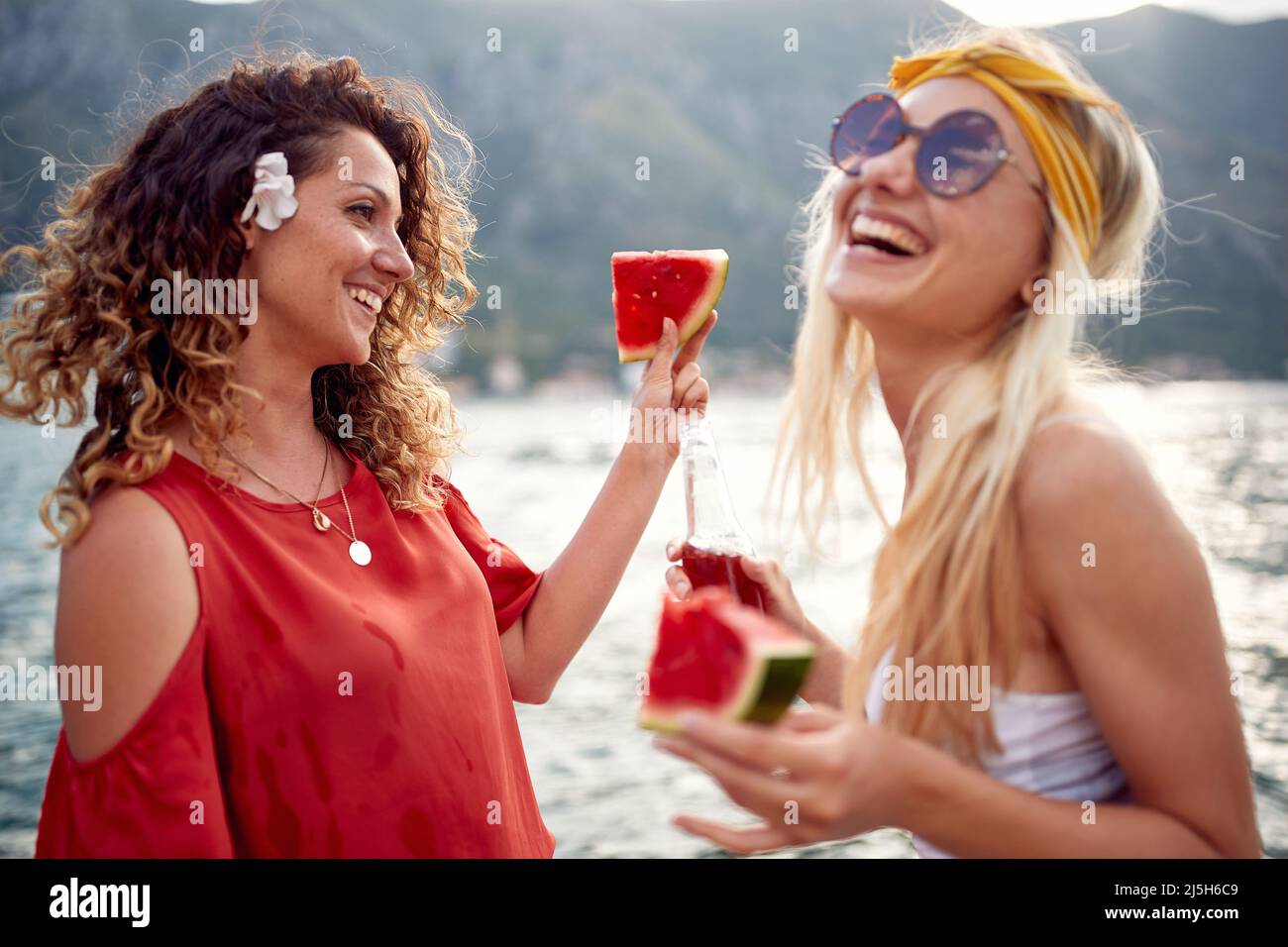 Happy Girls enjoying a day at the lake laughing and eating watermelon ...