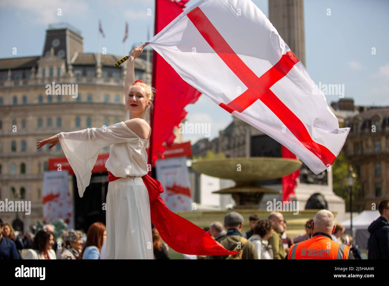 An Entertainer on stilts holds an English flag at the Saint George's ...