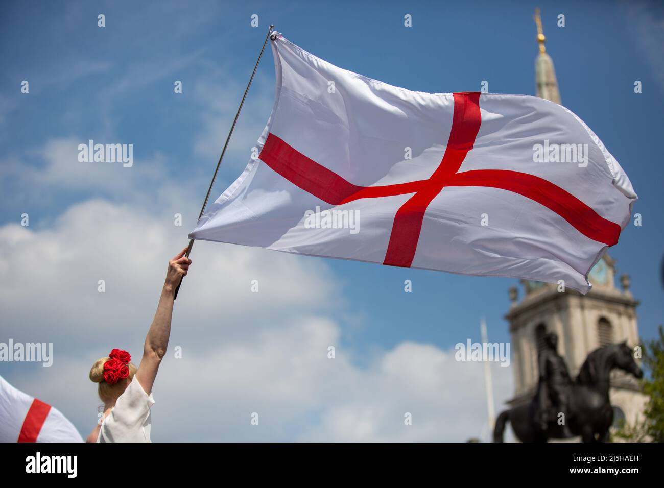 An Entertainer on stilts holds an English flag at the Saint George's ...