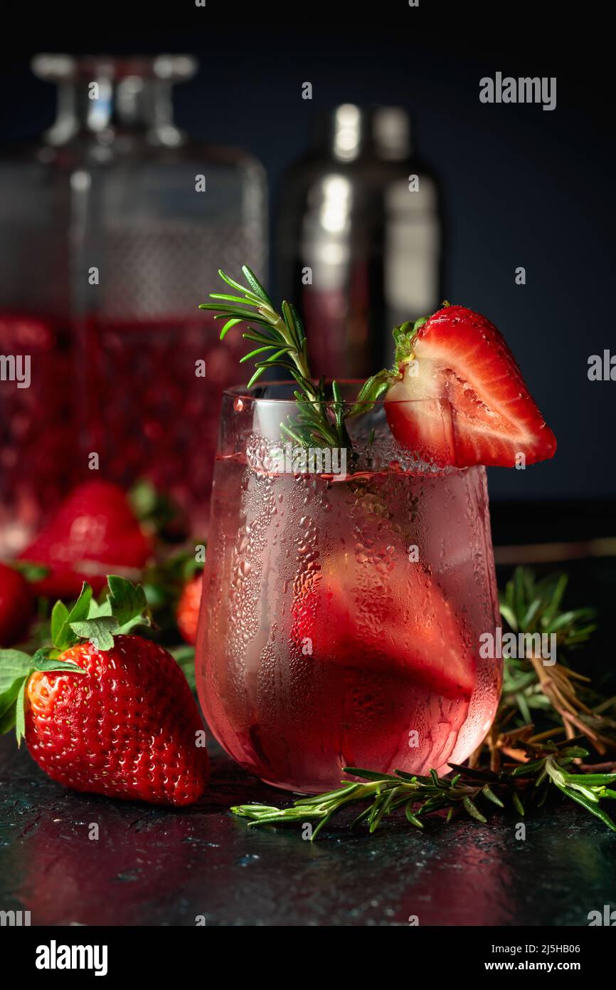 Cocktail gin tonic with ice, strawberries, and rosemary. A refreshing ...