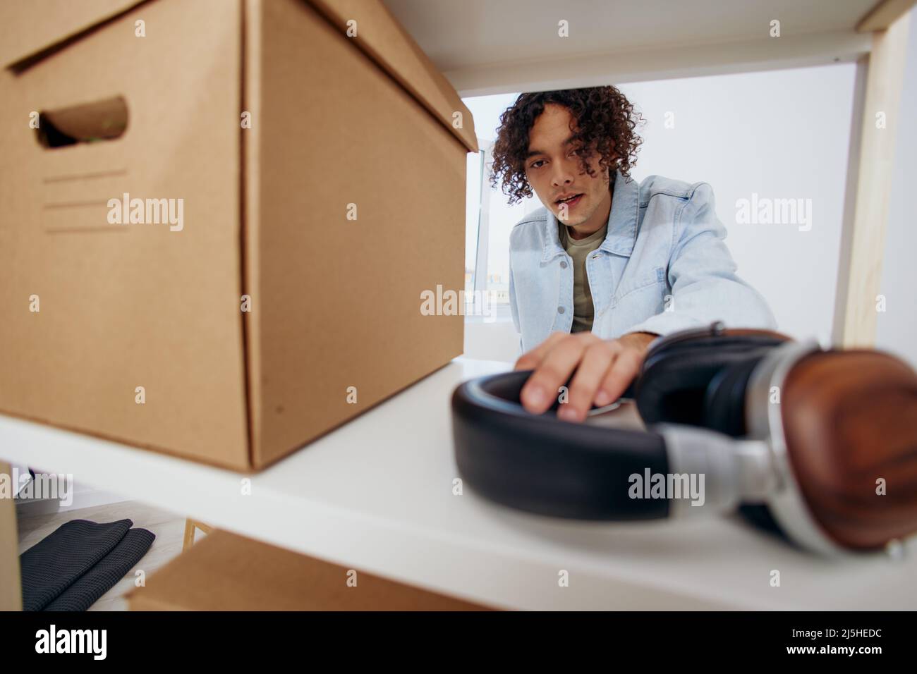 guy with curly hair unpacking things from boxes in the room sorting ...