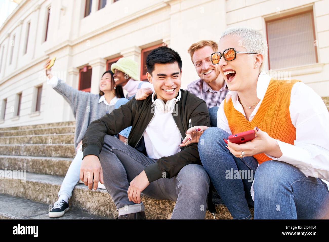 Big laugh of a woman with friends using mobile cell. Happy group of ...