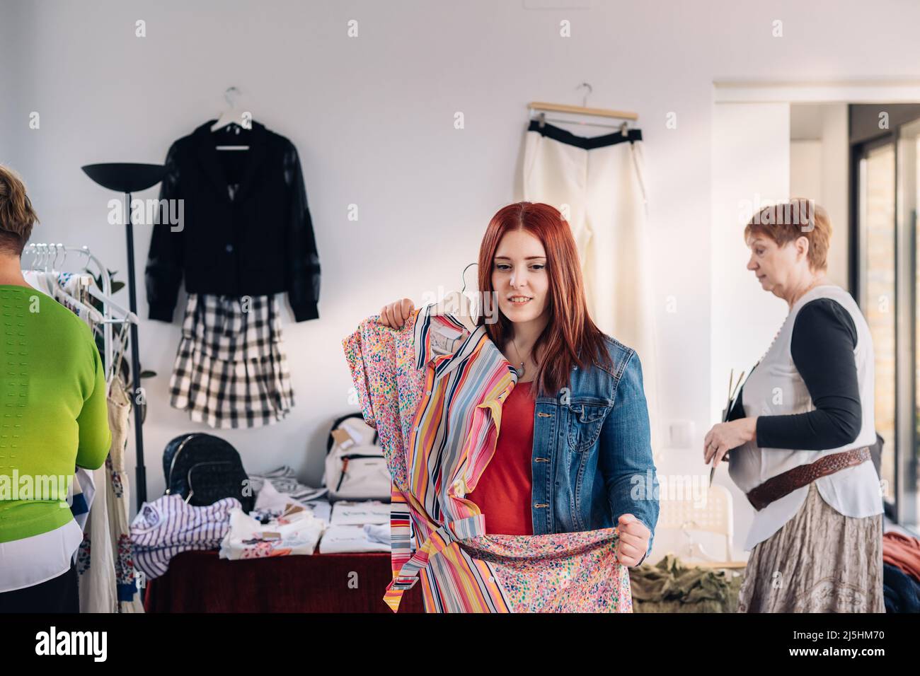 young woman testing a dress in front of a mirror. red-haired girl ...