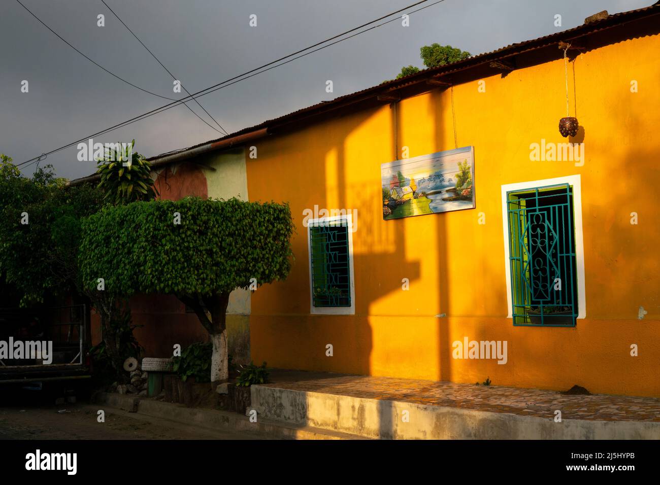Facade of an old yellow building along the street with tree and stormy ...