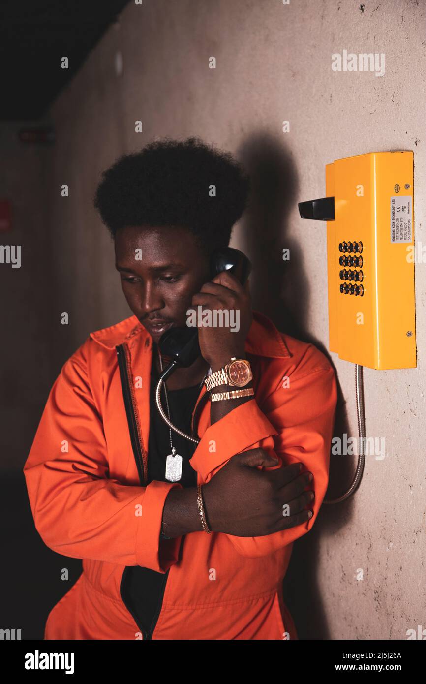 Black prisoner in an orange jumpsuit talking to the phone Stock Photo ...