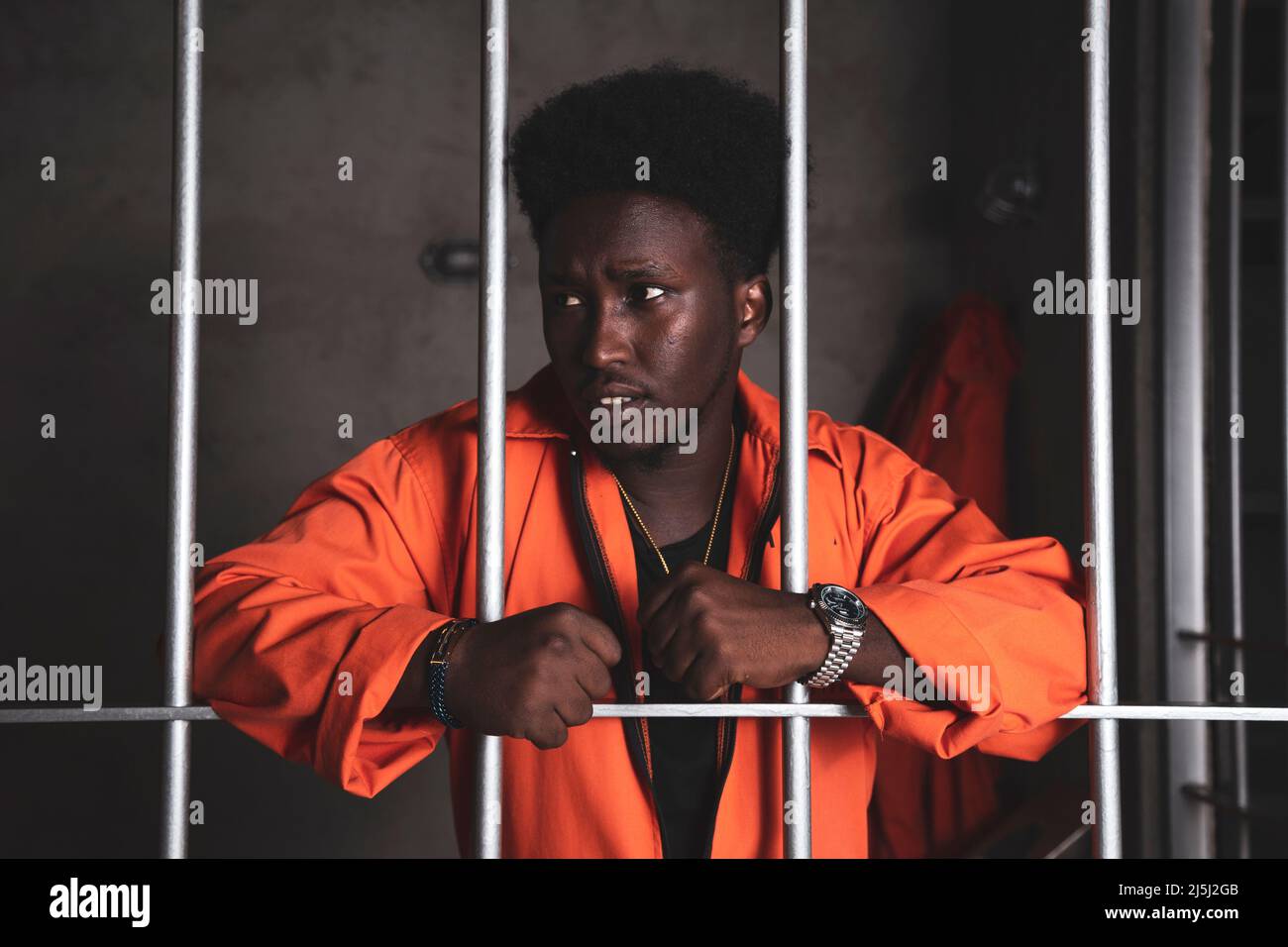 Black prisoner in an orange jumpsuit leaning his cell fence Stock Photo ...