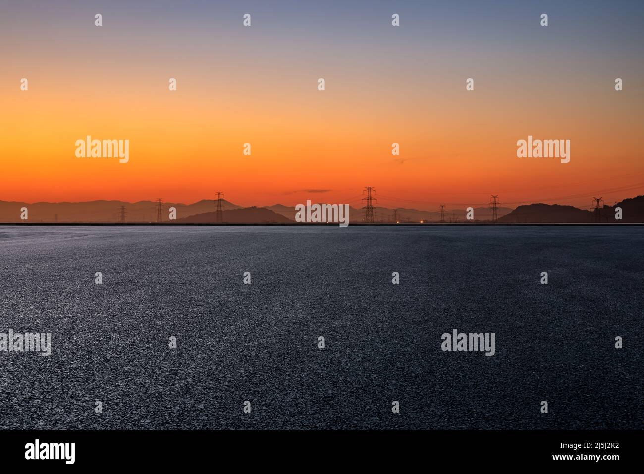 Asphalt road platform and mountain with high voltage power tower ...