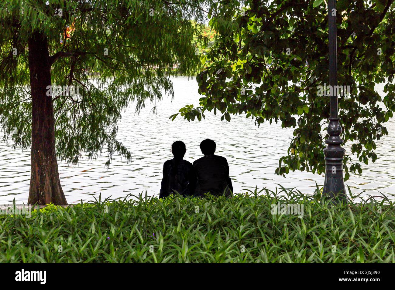 Two people together sitting in the grass looking at the lake in the Old ...