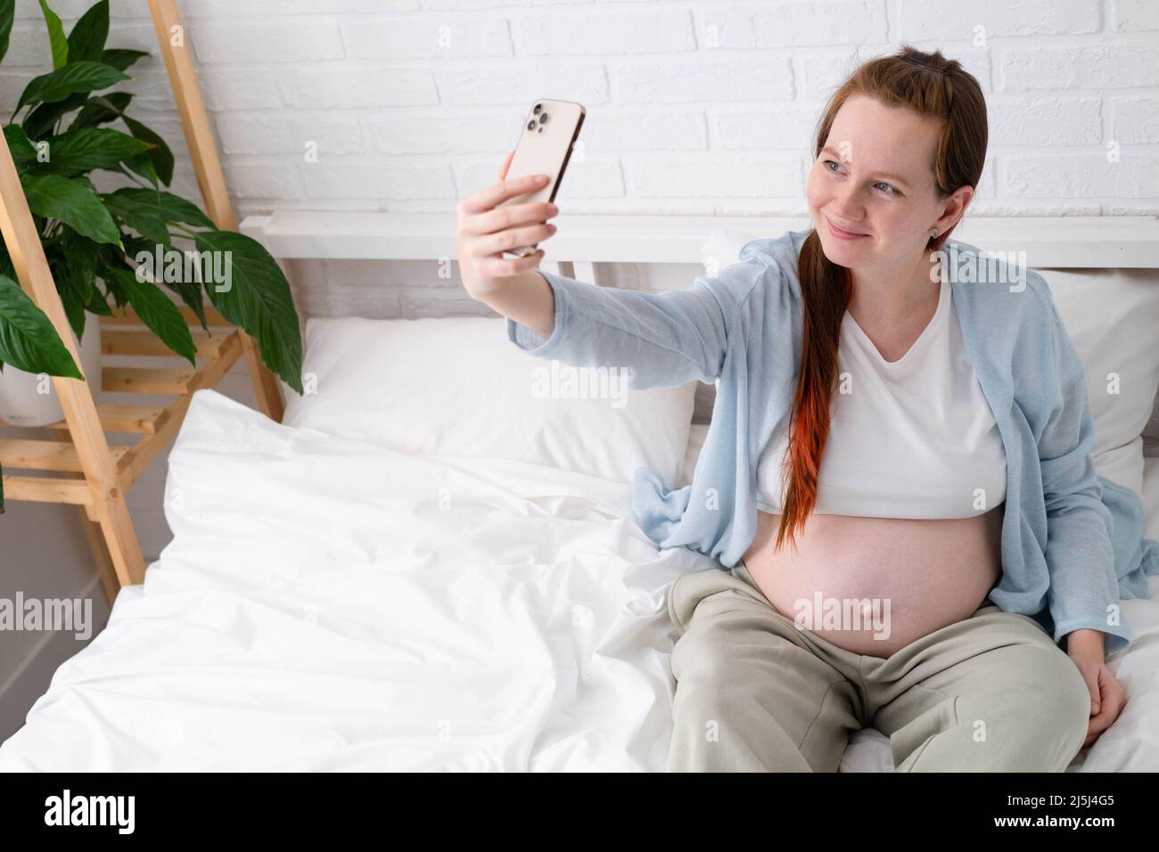 Beautiful cheerful pregnant woman taking selfie photo using mobile ...