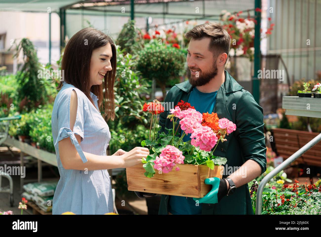 Worker helping female customer with plant in garden center Stock Photo ...