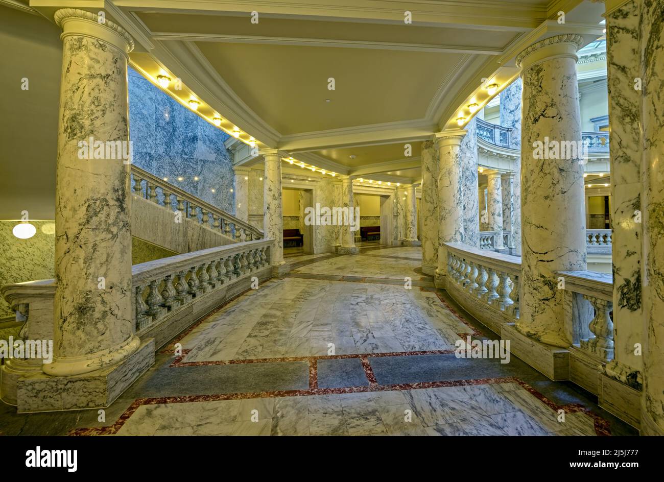 A hallway lined with balustrades circles around the atrium of the State ...