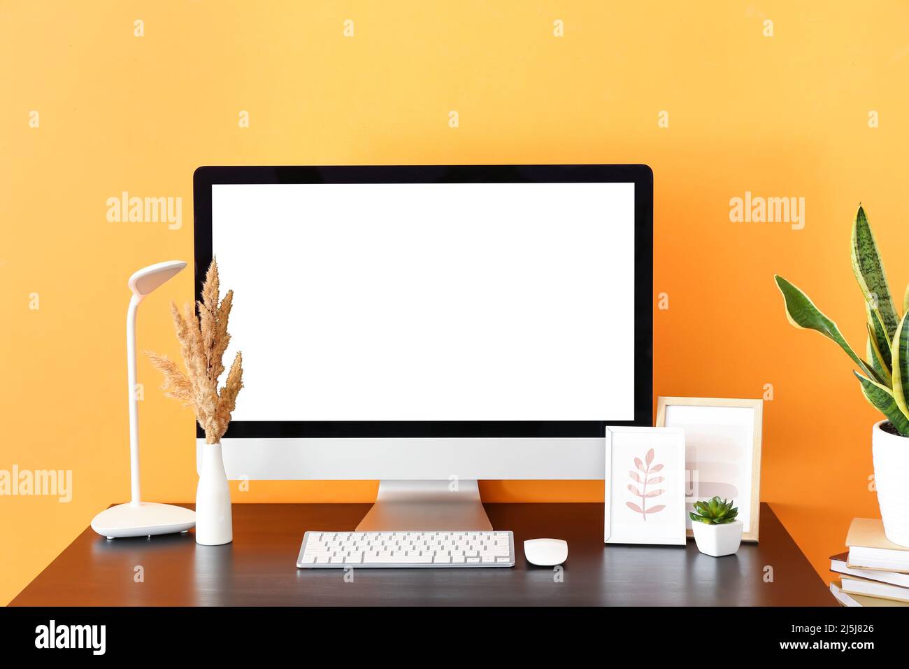 Workplace with modern computer, lamp and stylish decor near color wall ...