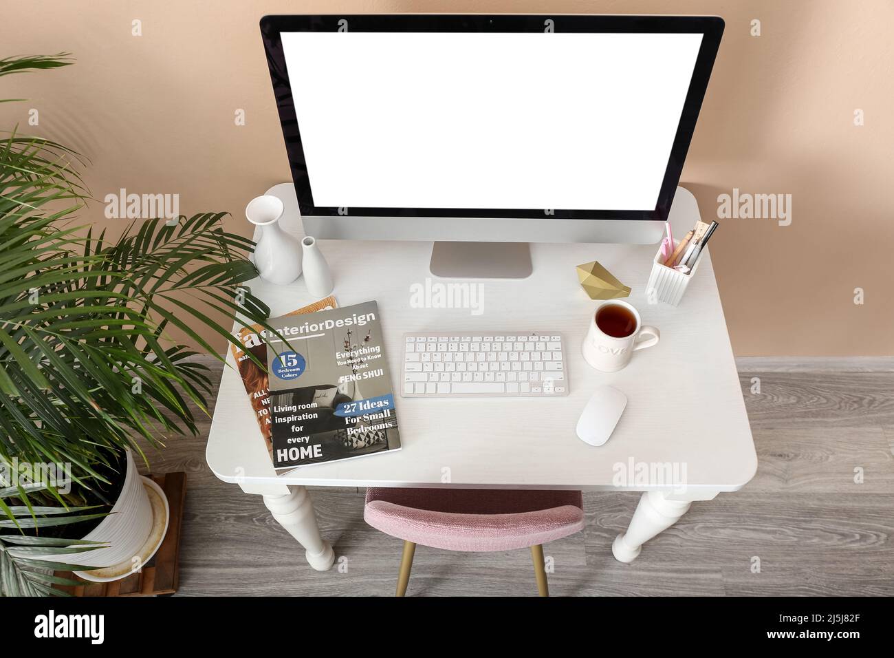 Modern workplace with computer, cup and magazines in room Stock Photo ...
