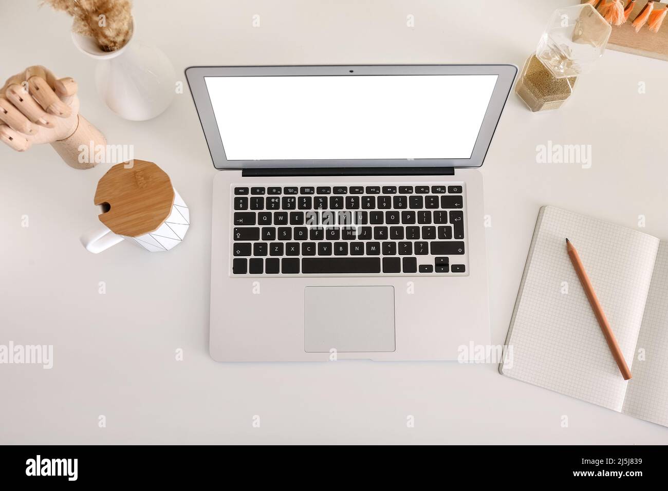 Modern laptop, cup, notebook and stylish decor on light table Stock ...