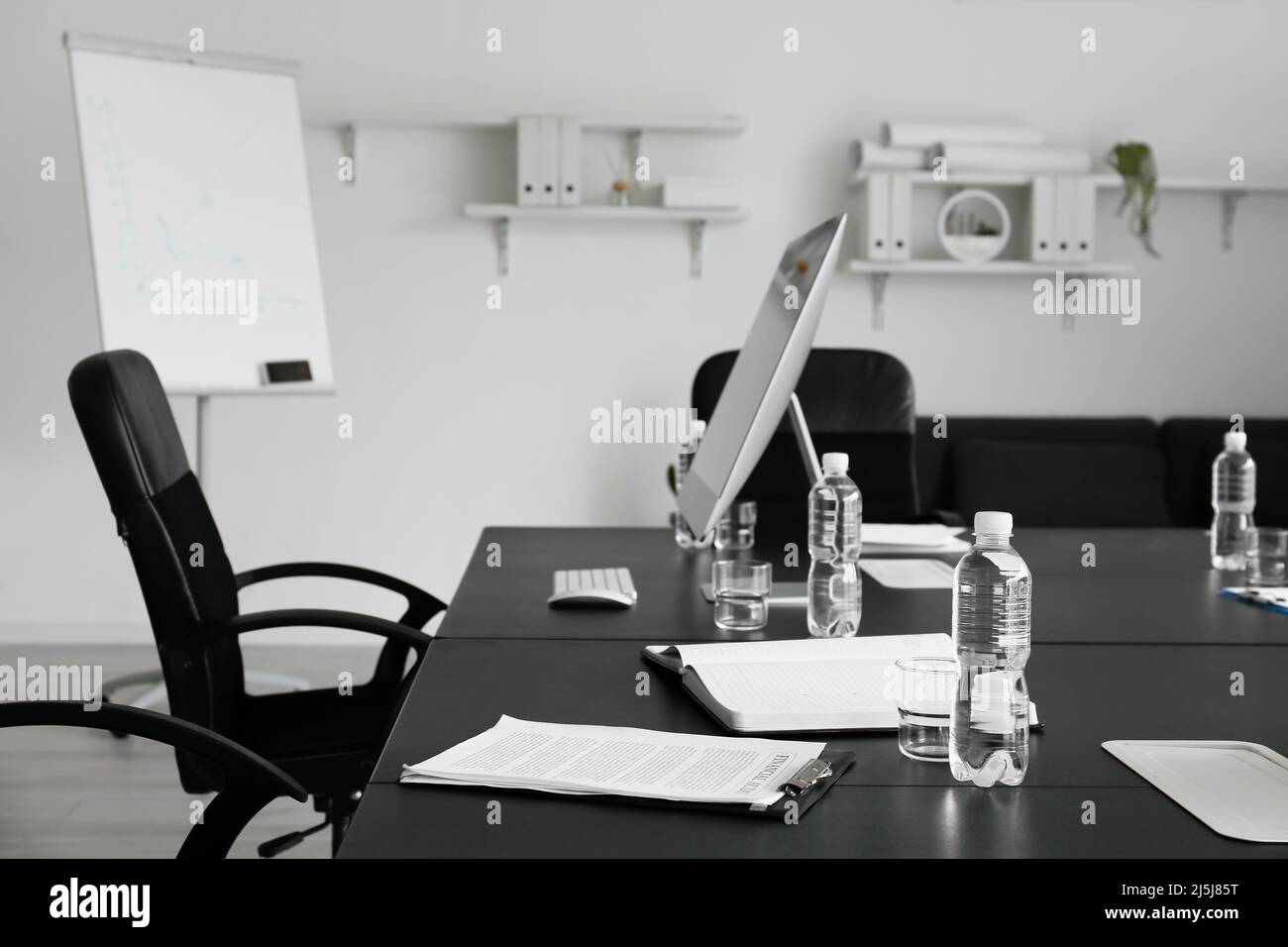 Table with modern computer and bottles of water in conference room ...