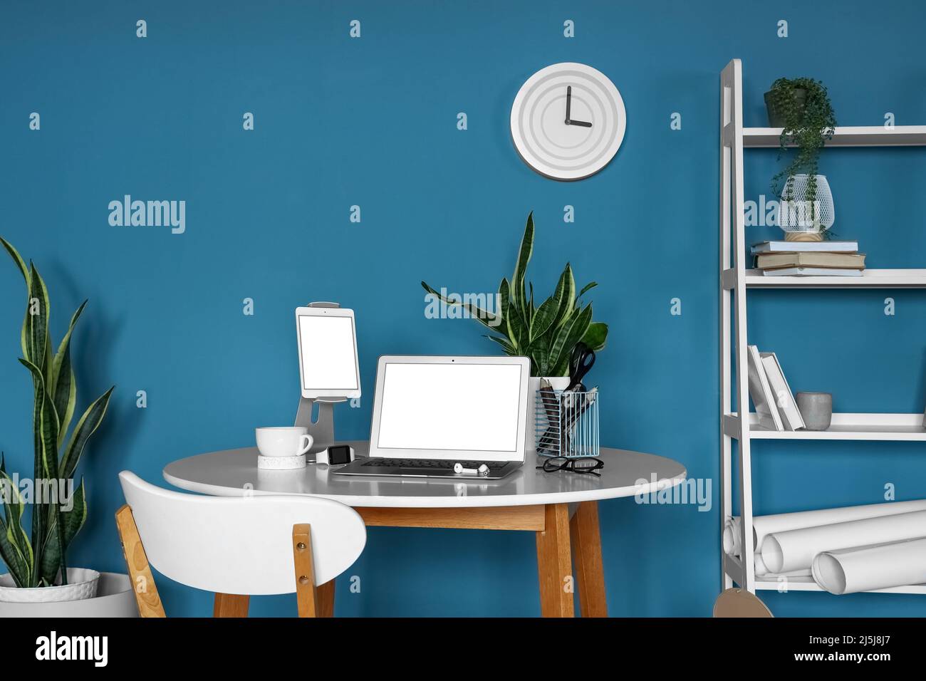 Workplace with modern gadgets and shelf unit near blue wall Stock Photo ...