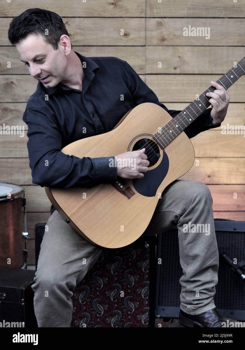 A guitarist plays acoustic steel string guitar in studio recording ...