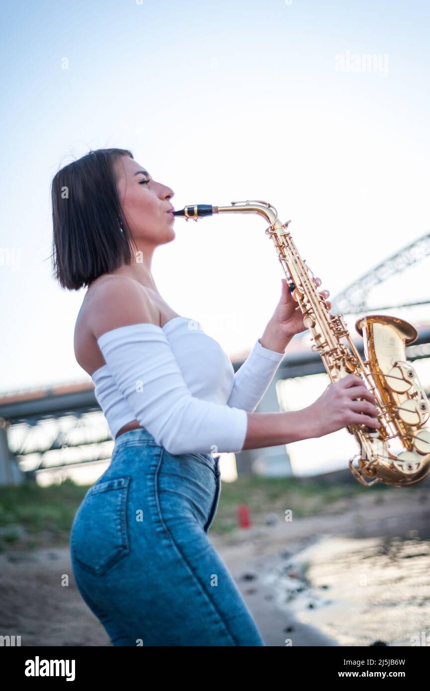Woman playing the saxophone at sunset Stock Photo - Alamy