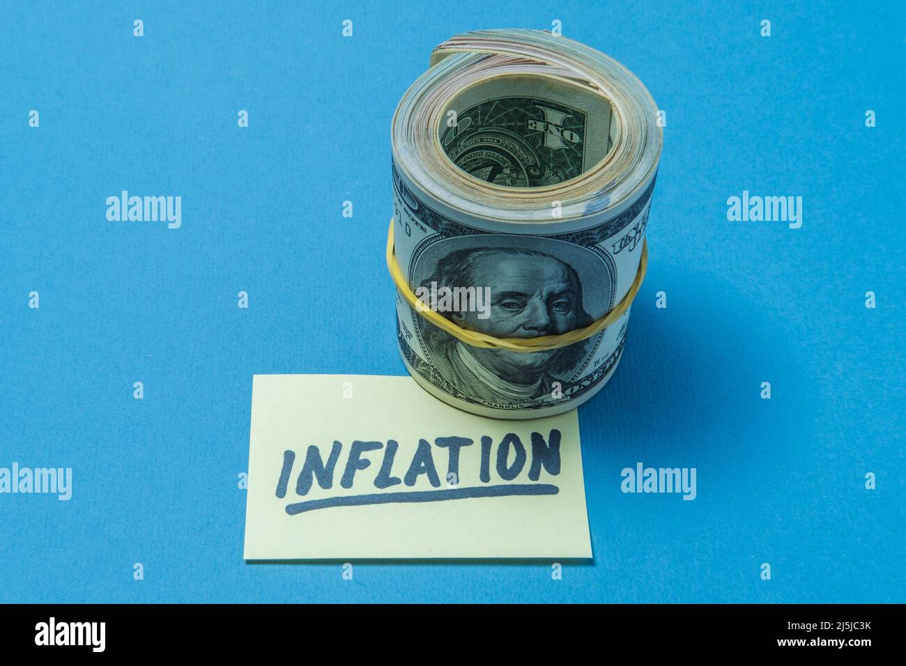 Dollars rolled into a tube with a poster that says inflation Stock ...